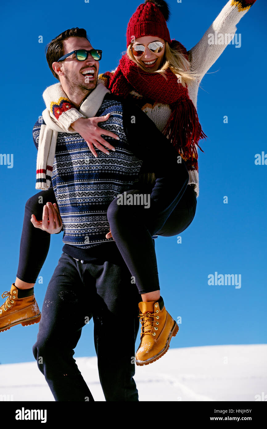 Couple playing in snow. Man giving woman piggyback ride on winter ...