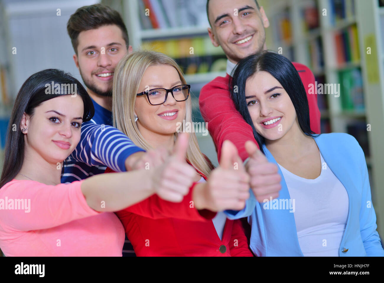 Cheerful group of students smiling at camera with thumbs up, success ...