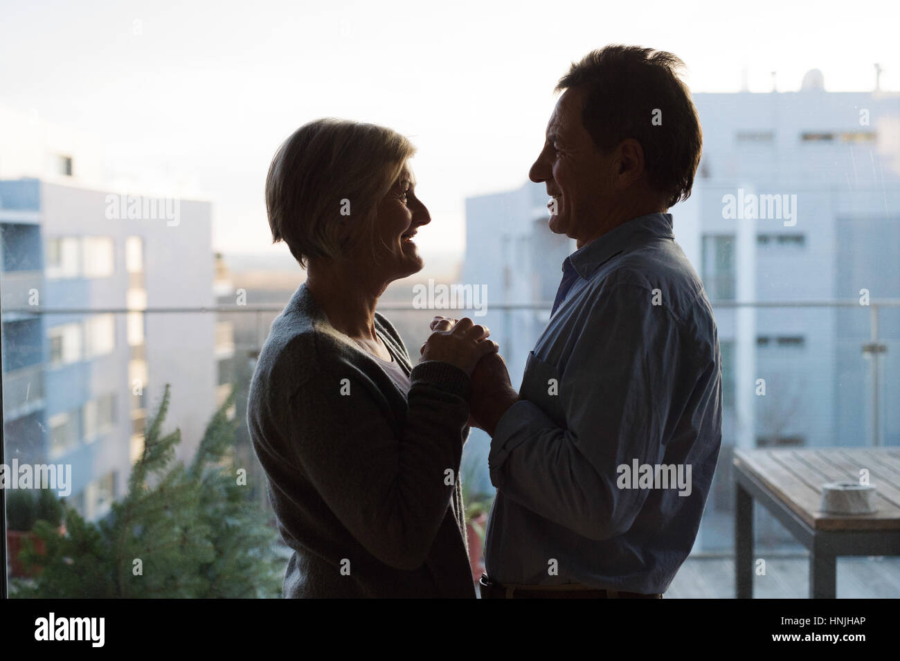 Silhouette of senior couple standing on balcony, holding hands Stock ...