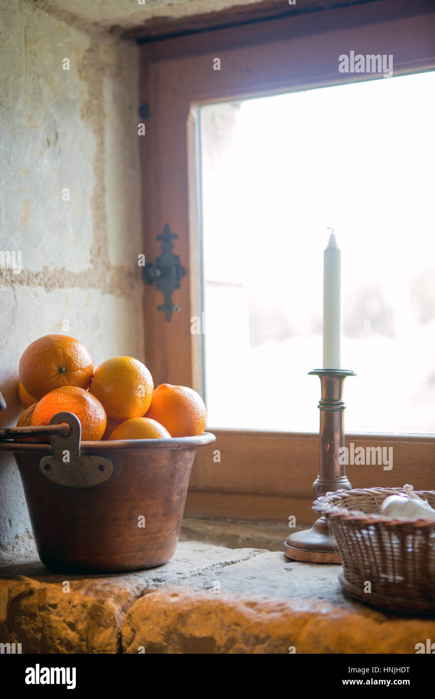 Window still life with bowl of oranges, candle, and garlic cloves. Old ...