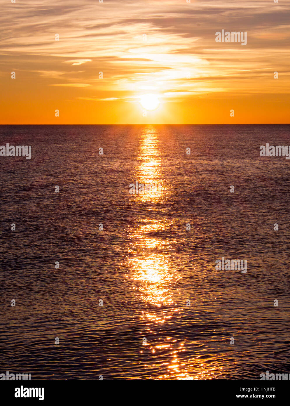 low sunset sun with sunbeam in the centre casting long highlight from ...