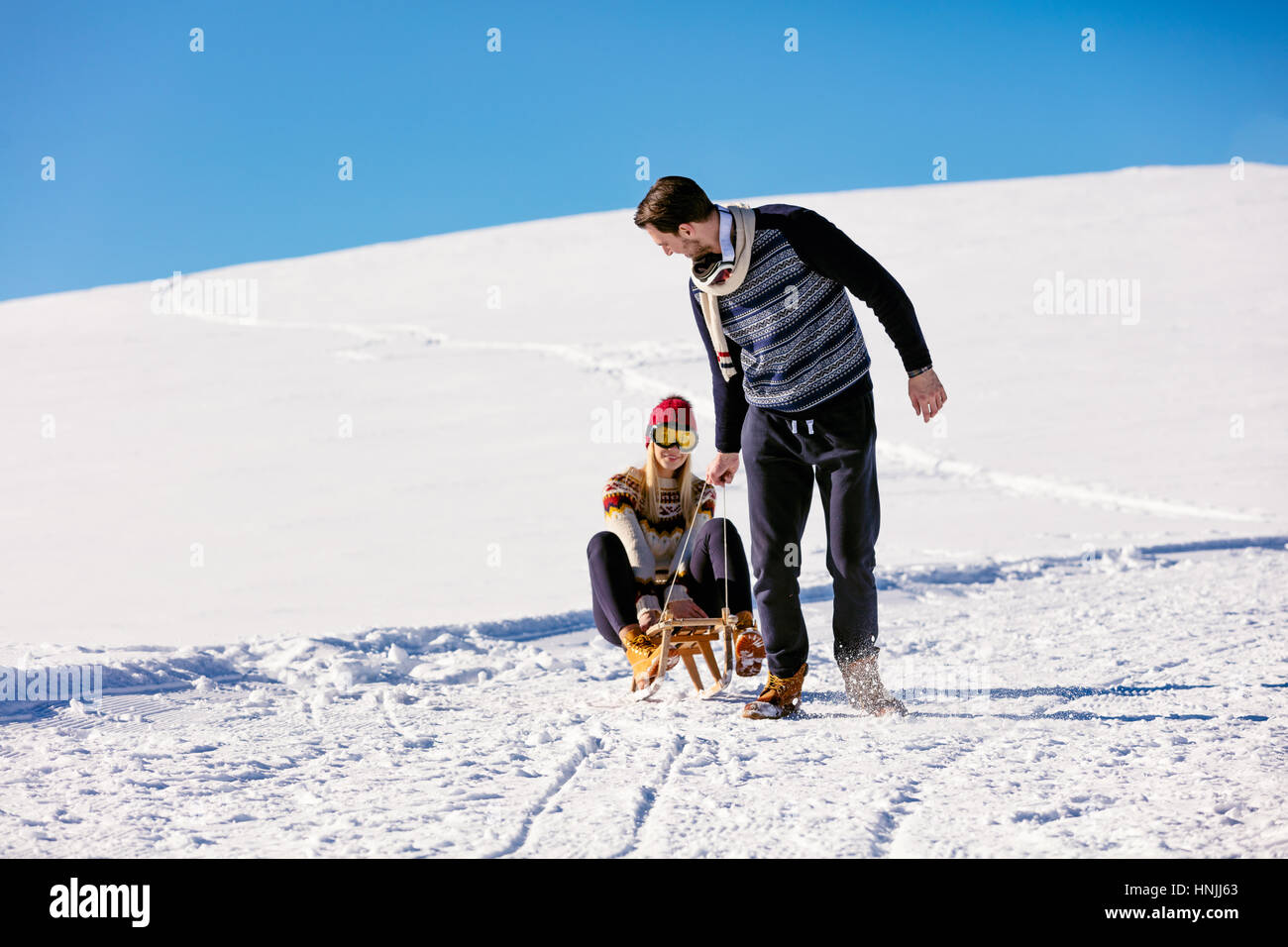 Man pulling girl on a sled at snow - concept: Winter fun Stock Photo ...