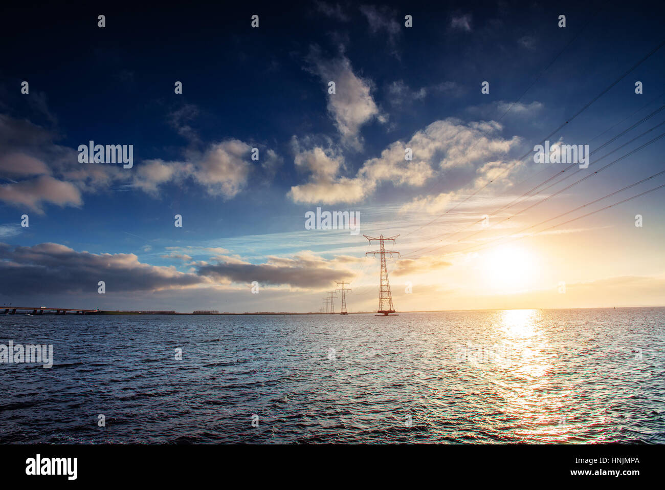 electric line above water during a fantastic sunset Stock Photo - Alamy