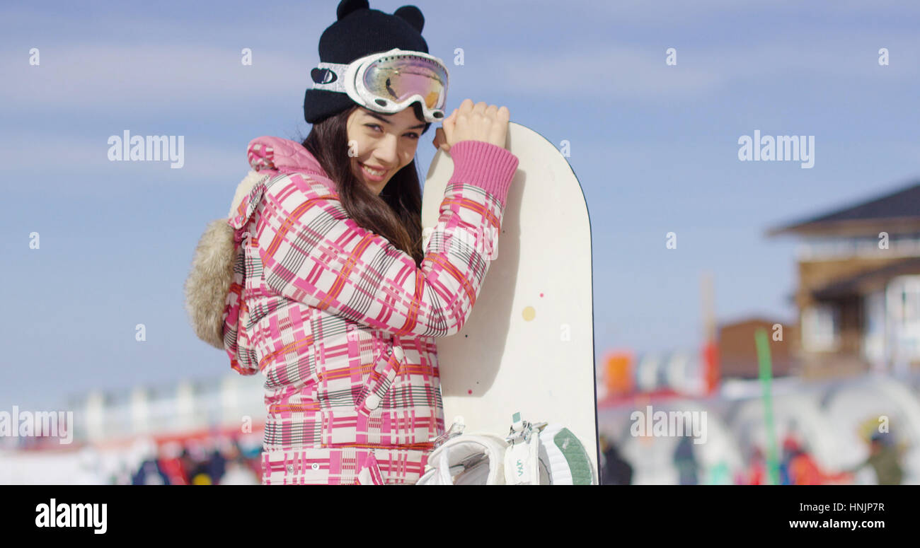 Cute asian female snowboarder relaxing on ski slope. She standing with ...