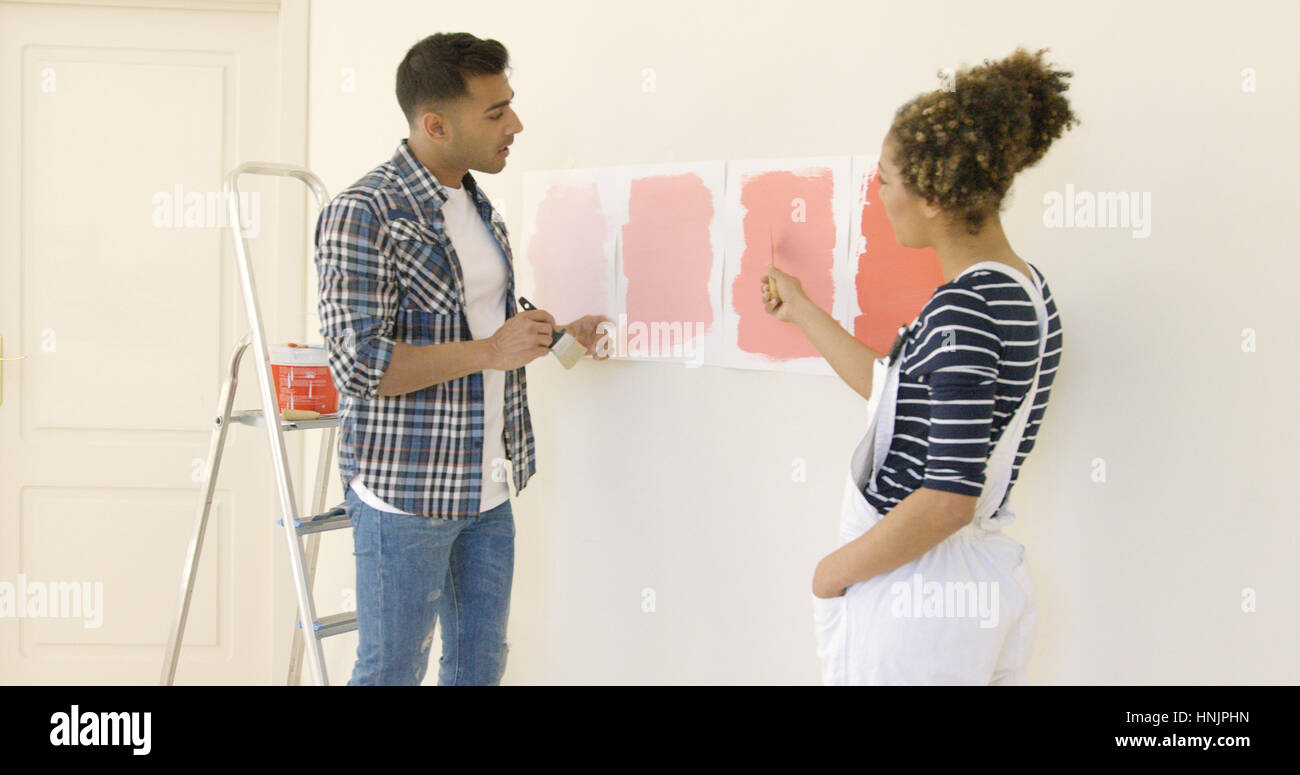 Young couple debating a new paint color for the wall of their home as ...