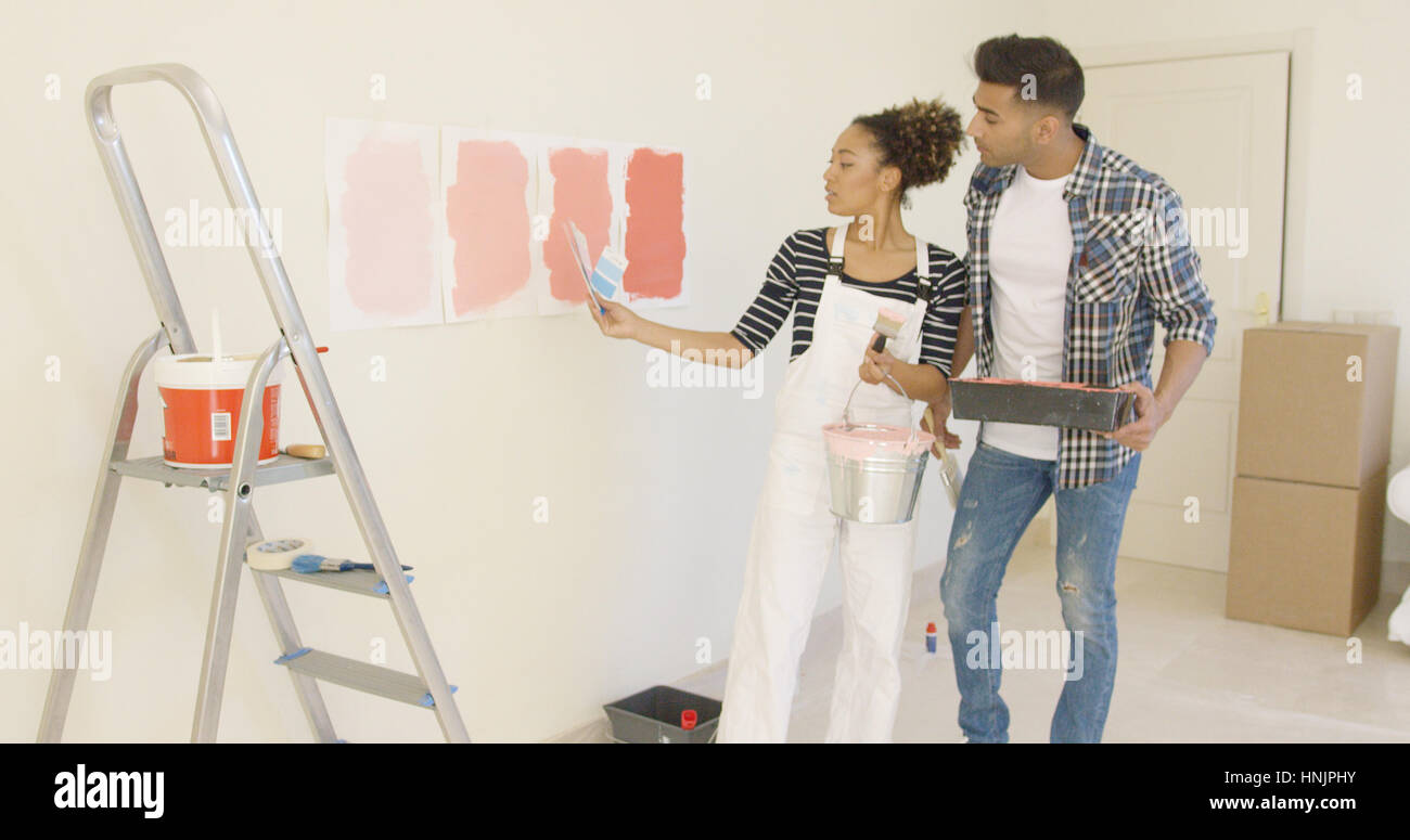 Young couple discussing shades of paint color together as they renovate ...