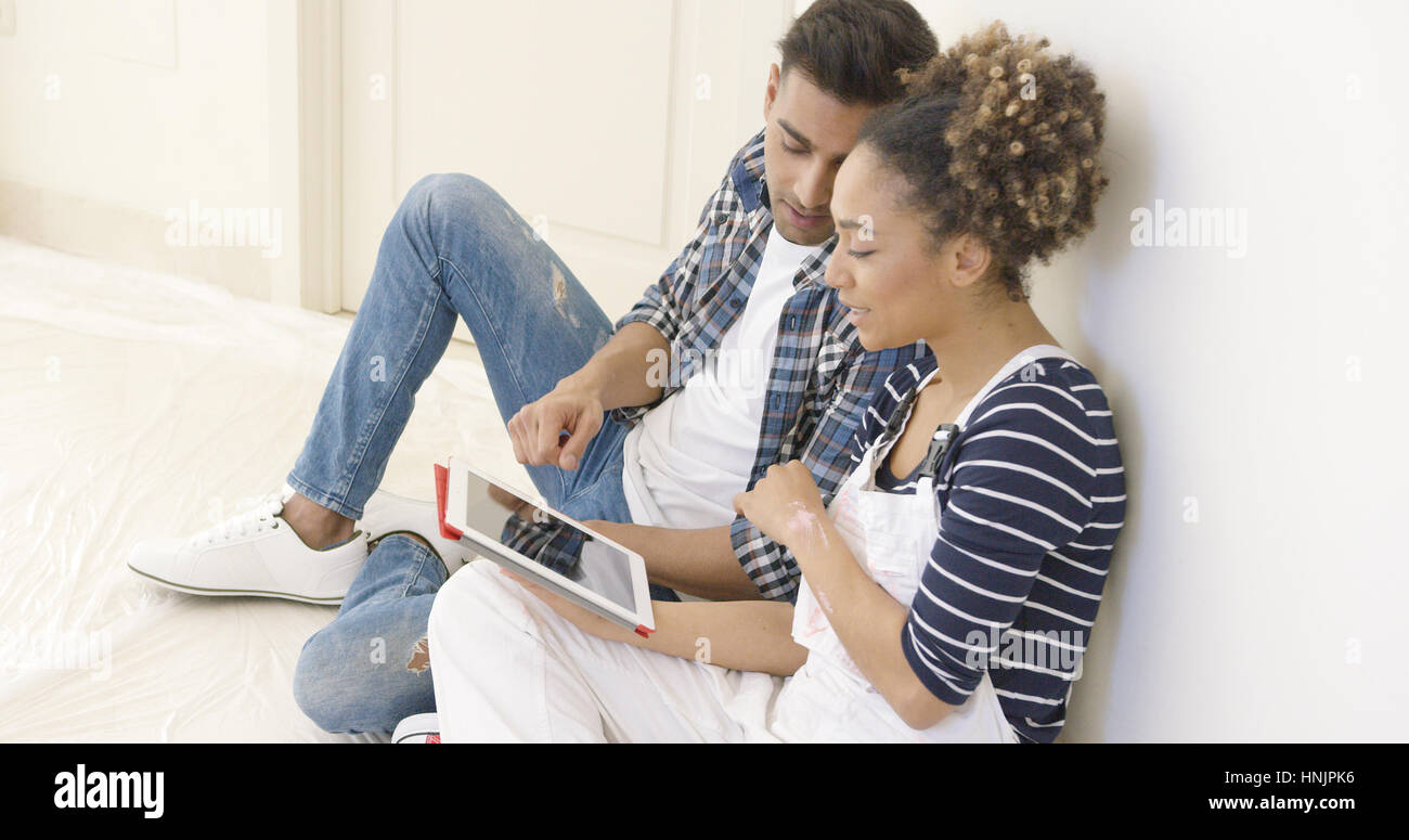 Handsome black couple sits and uses tablet while seated on tarpaulin ...