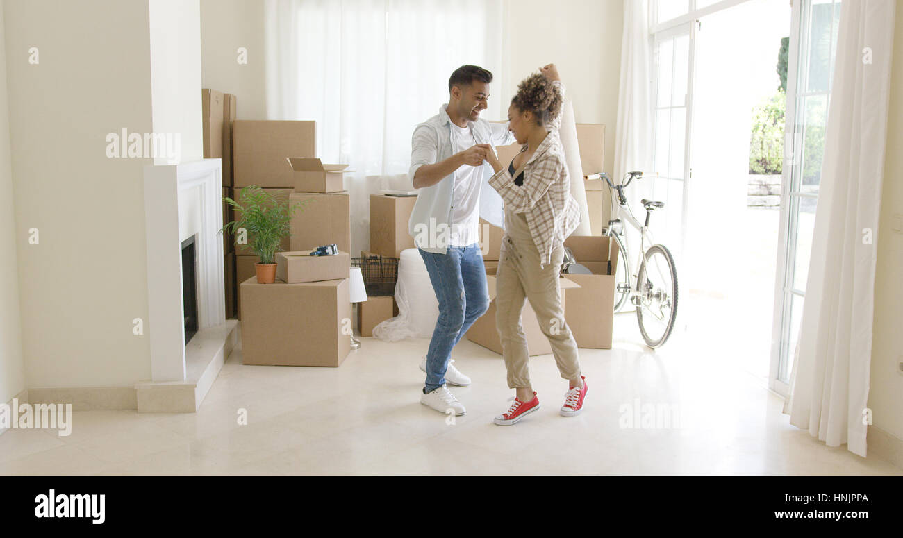 Happy young couple celebrating moving home dancing together in the ...