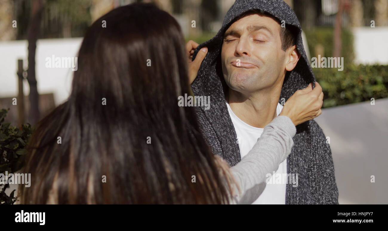 Young man goofing around outdoors with his girlfriend pulling a comical ...