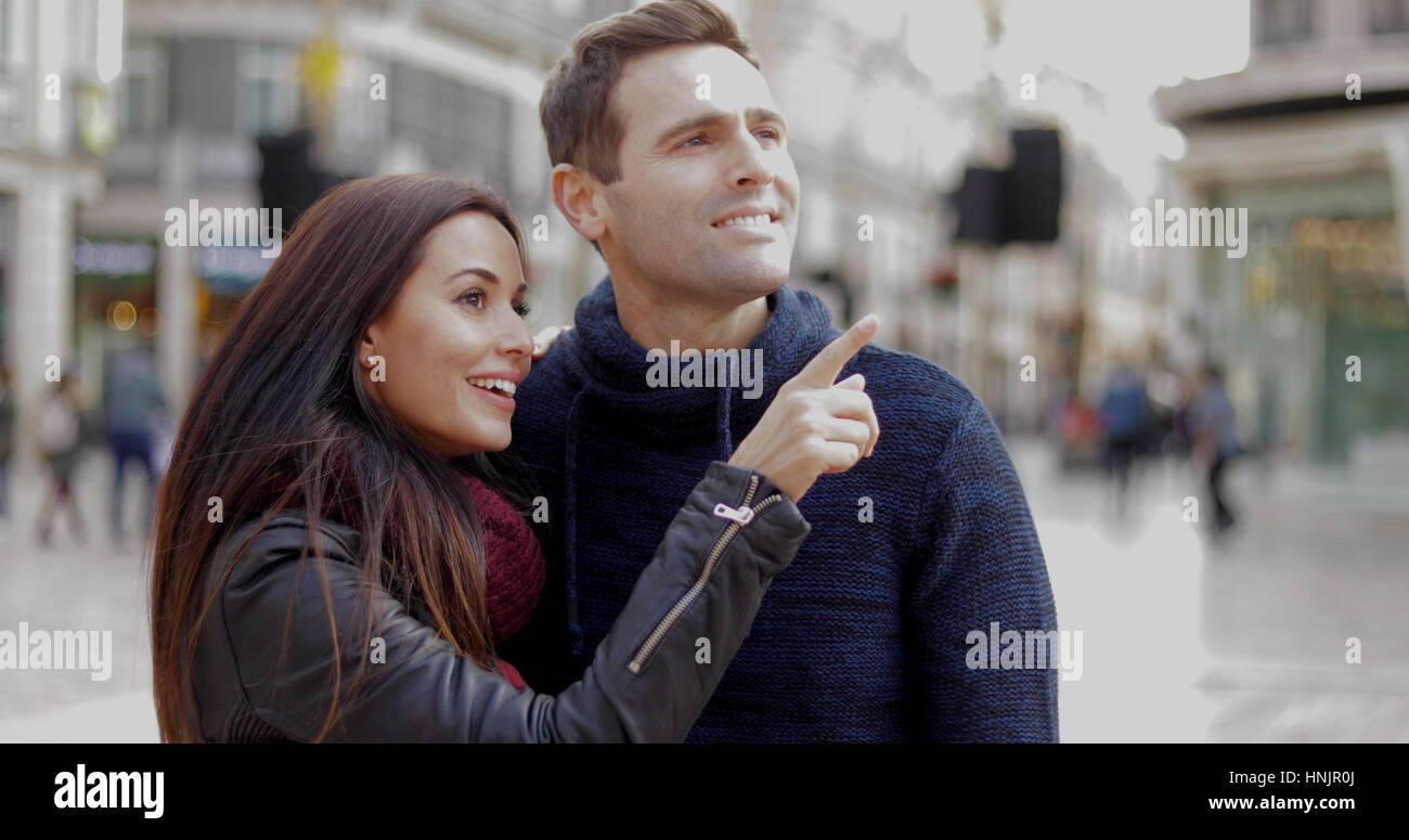 Attractive young woman pointing out something in an urban square to her ...
