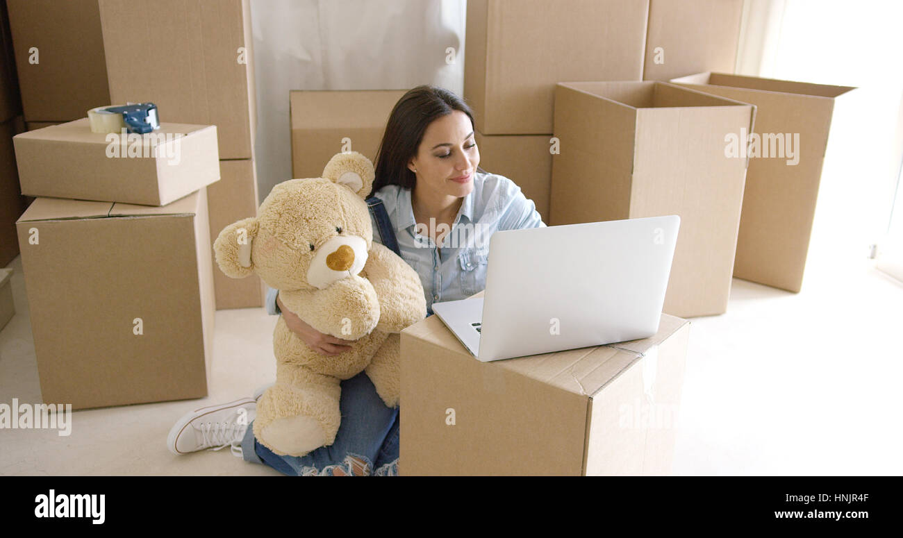 Young woman moving house with her large cuddly plush teddy bear sitting ...