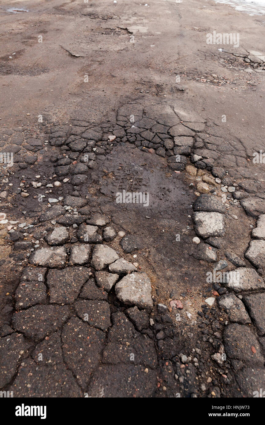 very bad crumbling asphalt road with holes and cracks. Photo taken ...