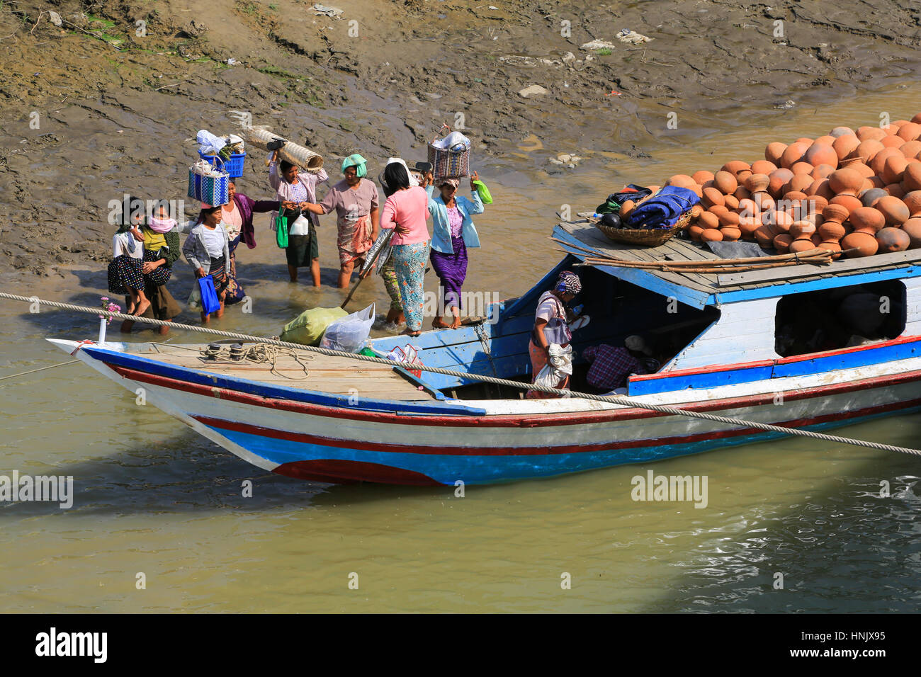 Local people are wading through the water with their shopping to board ...