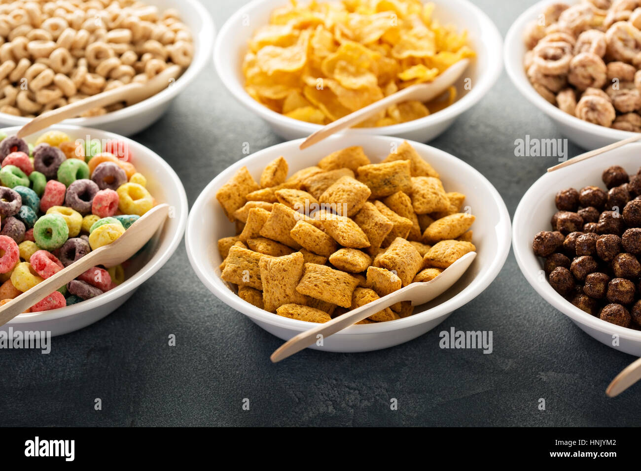 Variety of cold cereals in white bowls with wooden spoons, quick ...