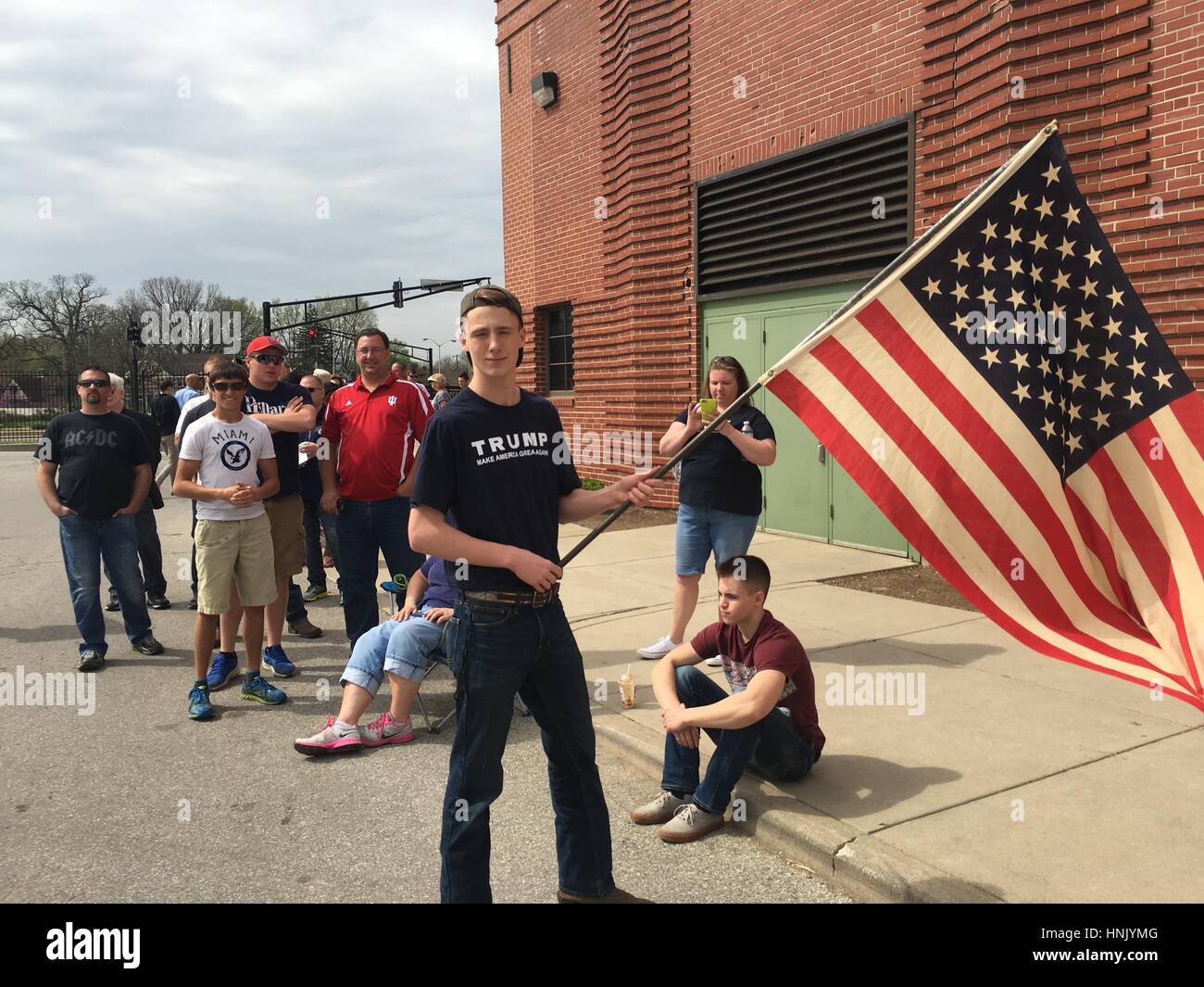 A Trump supporter holds an American flag while waiting in line before ...