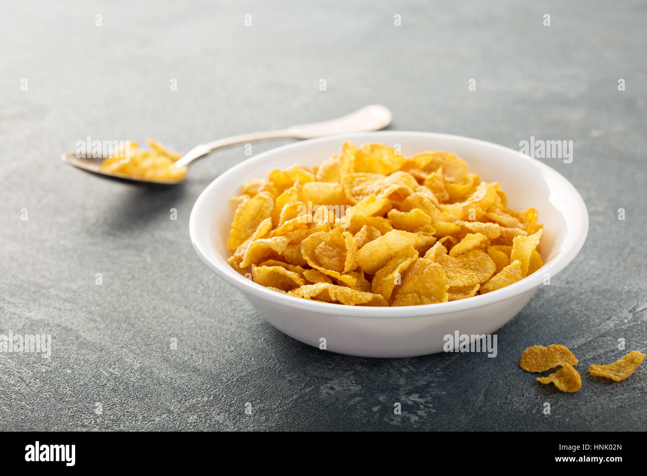 Cornflake cereals in a bowl with spoon on blue background, quick ...