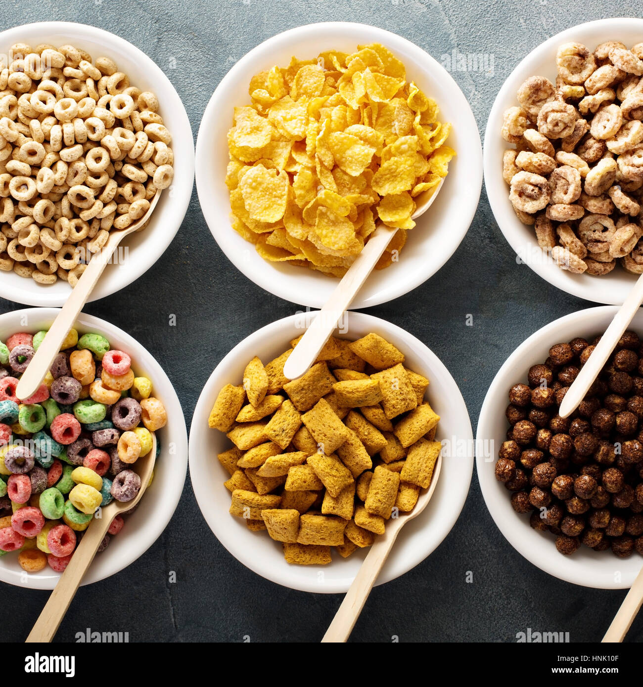 Variety of cold cereals in white bowls with wooden spoons, quick ...