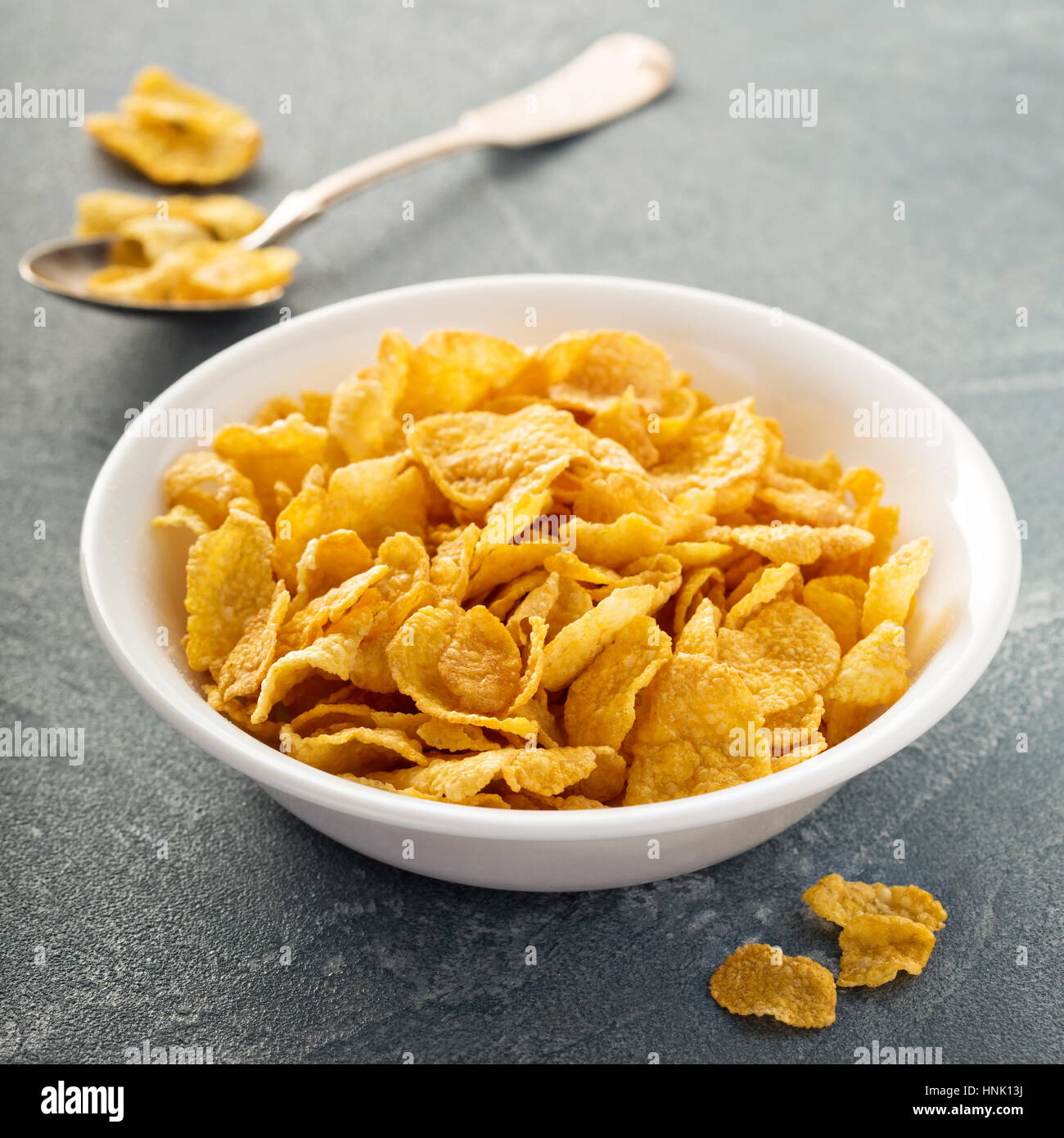 Cornflake cereals in a bowl with spoon on blue background, quick ...