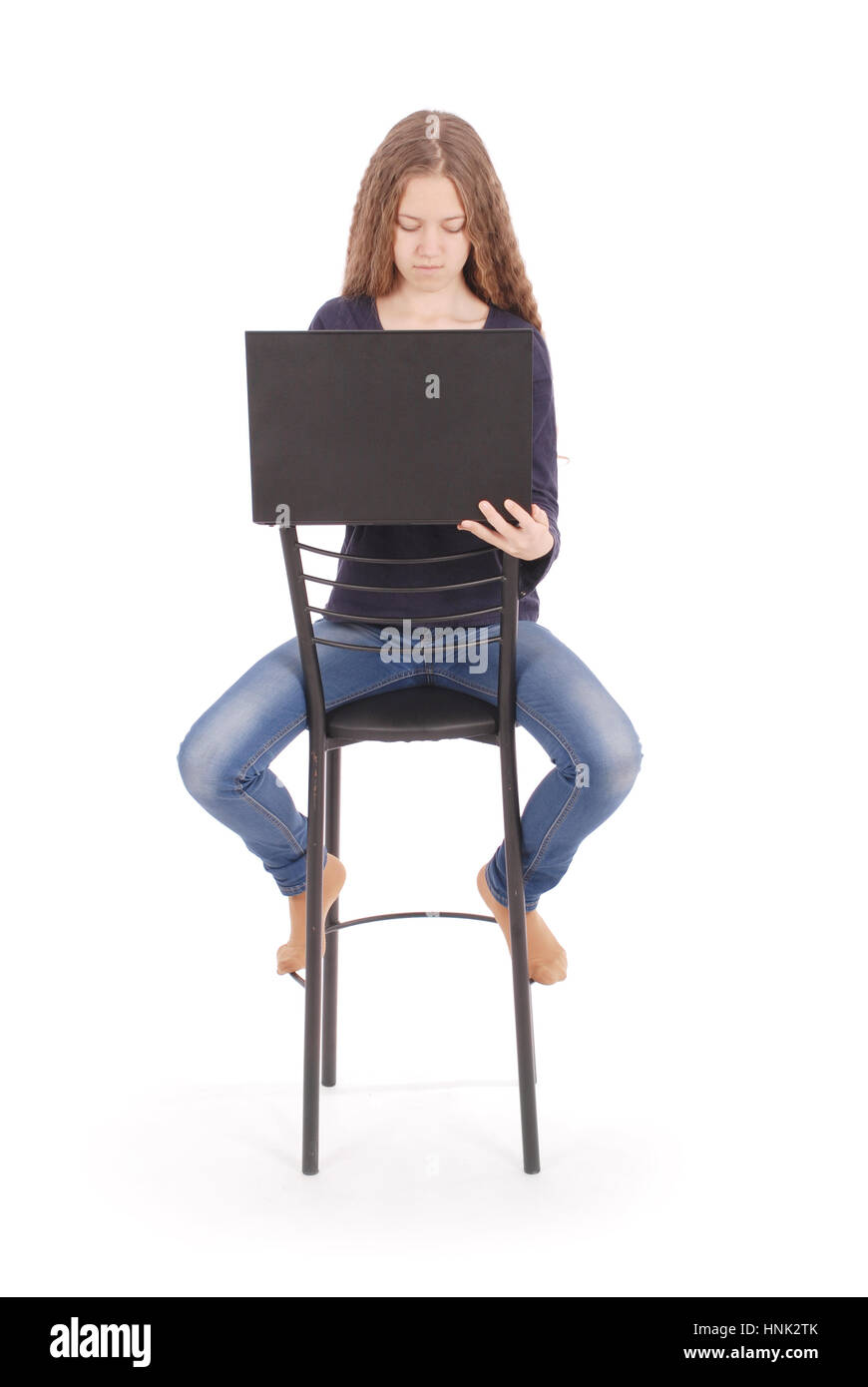 Girl sits on a chair and holding a laptop computer isolated on white ...
