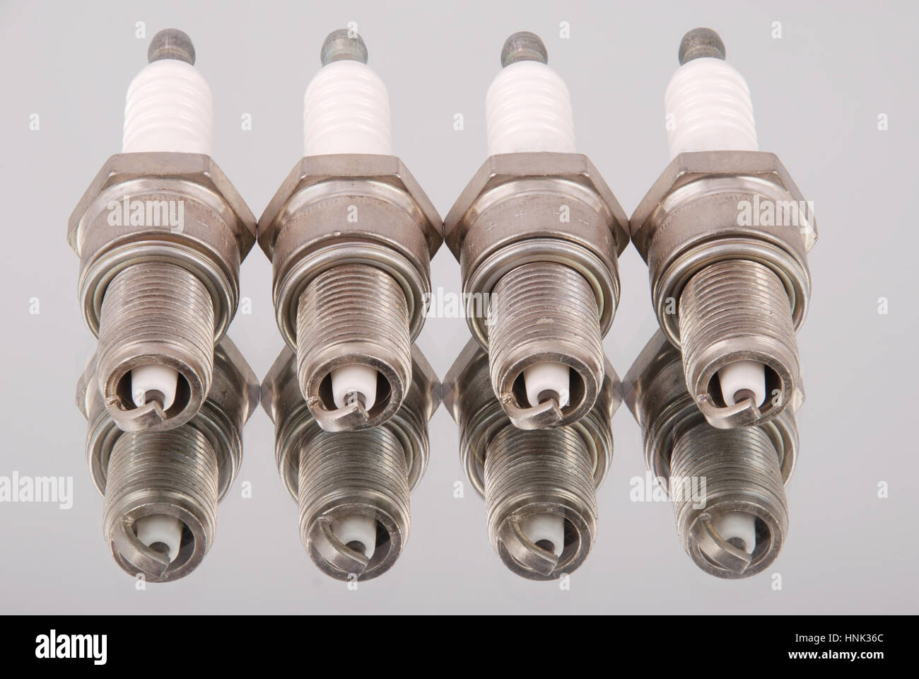 Four new spark plugs on a mirror background Stock Photo - Alamy