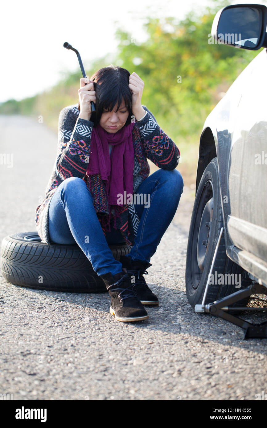 Woman changing a wheel on a car on the empty road, Selective focus and ...