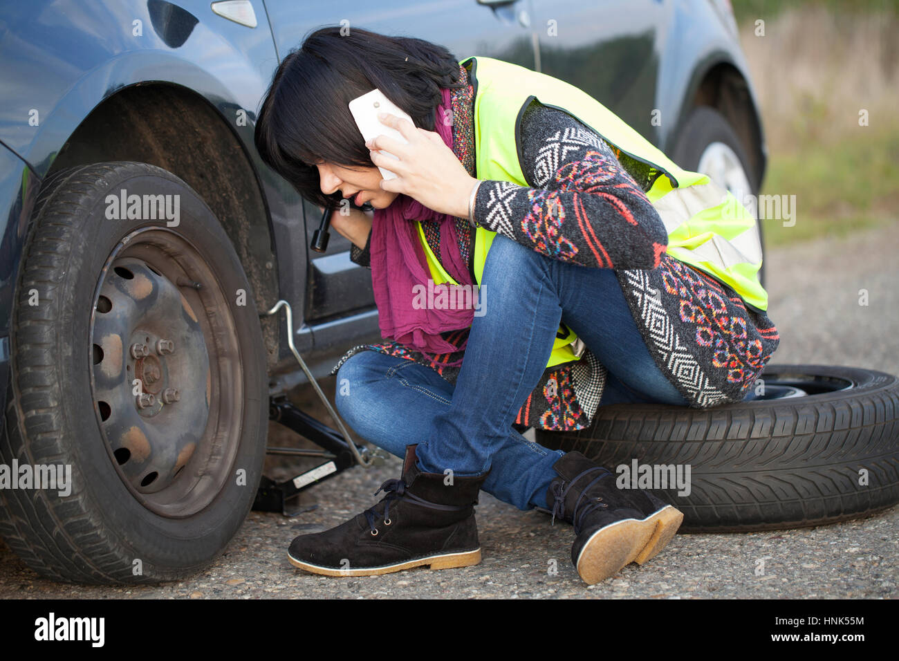 Woman changing a wheel on a car on the empty road, Selective focus and ...
