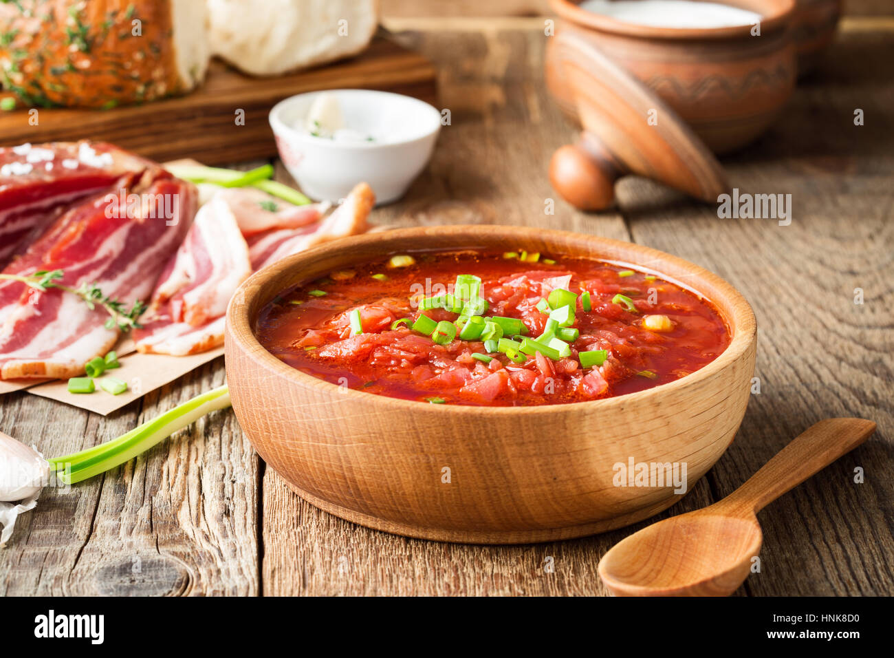 Traditional Ukrainian beet soup borscht in wooden bowl with garlic buns ...