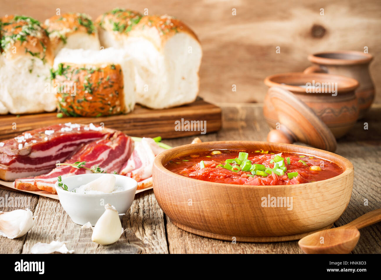 Traditional Ukrainian beet soup borscht in wooden bowl with garlic buns ...