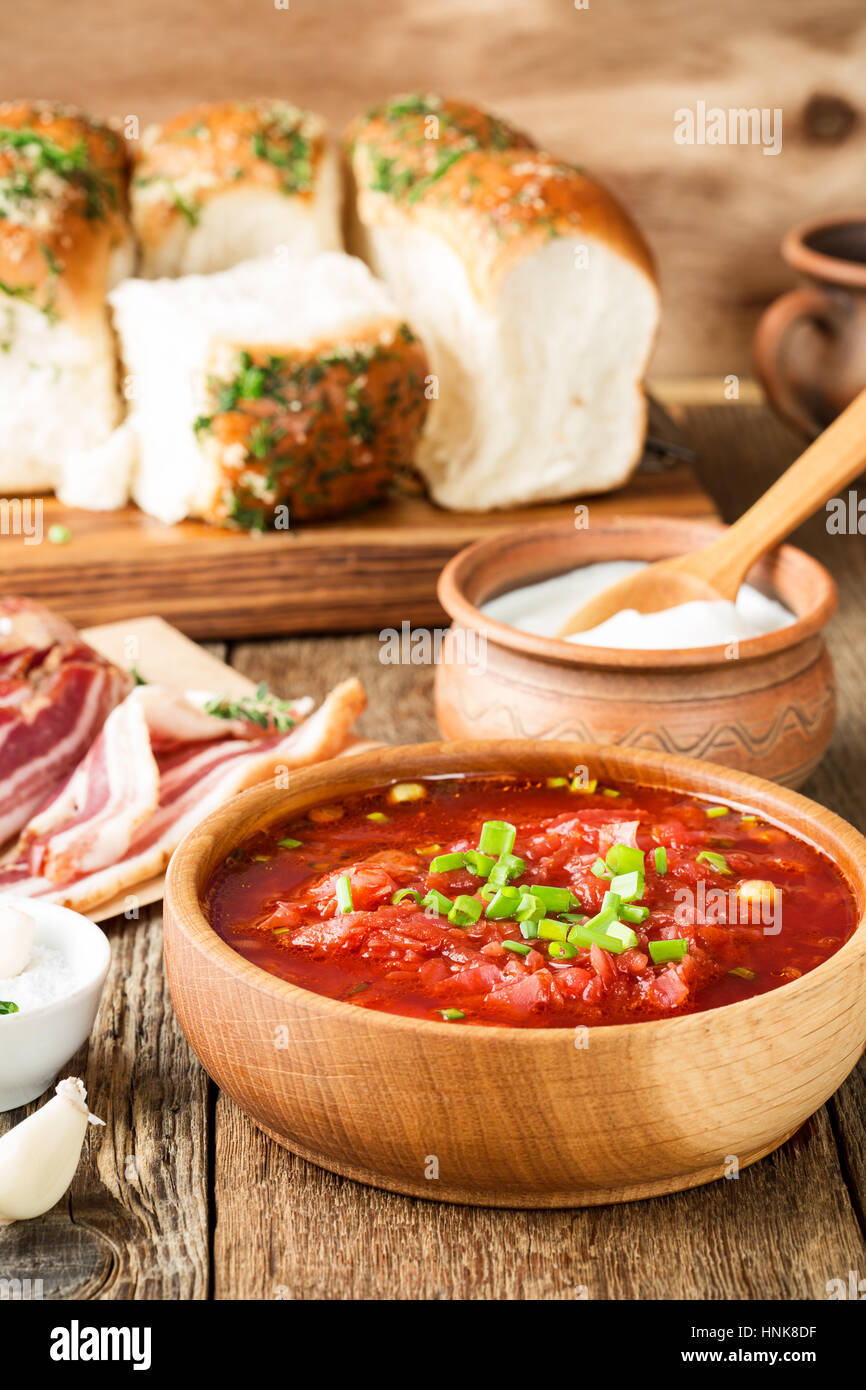Traditional Ukrainian beet soup borscht in wooden bowl with garlic buns ...