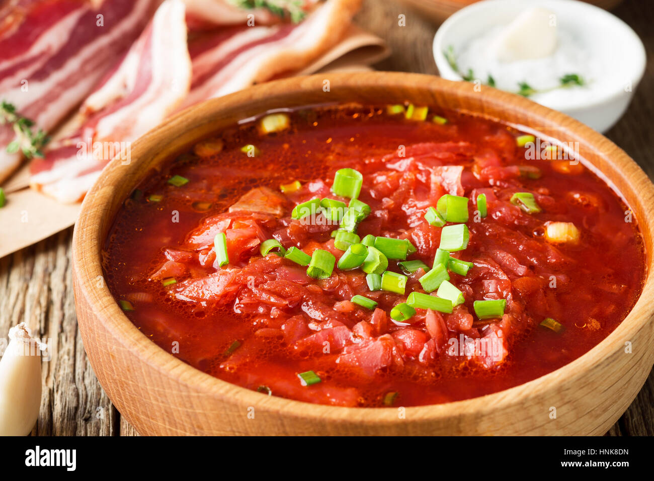 Traditional Ukrainian beet soup borscht in wooden bowl with garlic buns ...