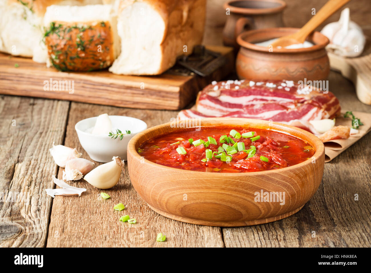 Traditional Ukrainian beet soup borscht in wooden bowl with garlic buns ...