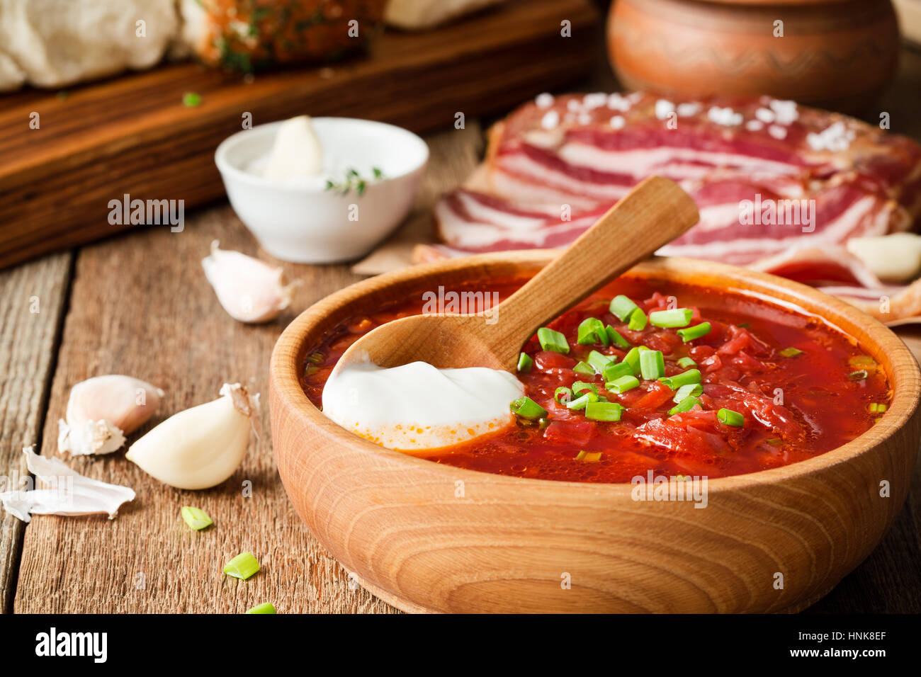 Traditional Ukrainian beet soup borscht in wooden bowl with garlic buns ...