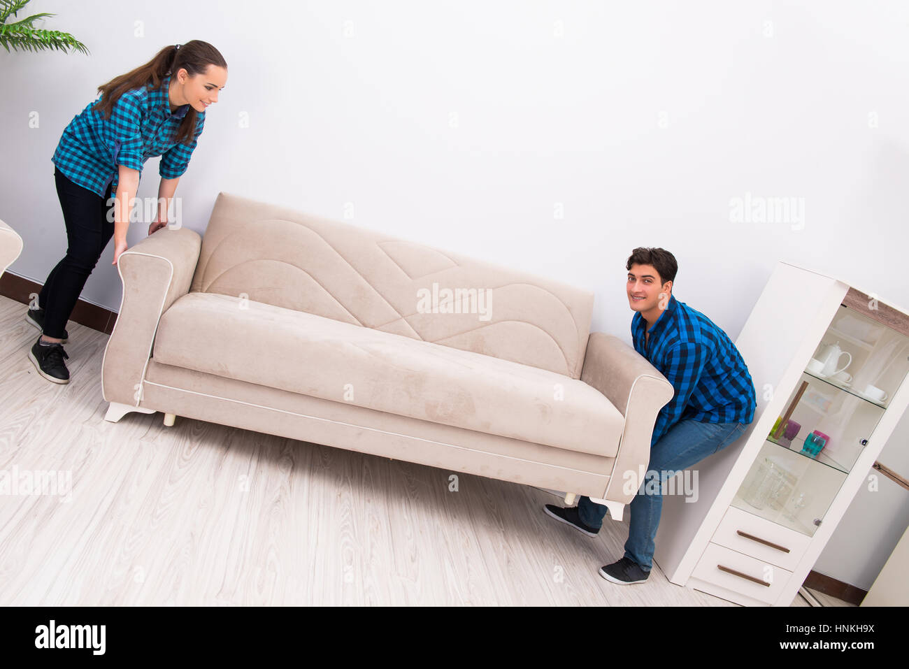 Wife and husband moving sofa couch Stock Photo - Alamy