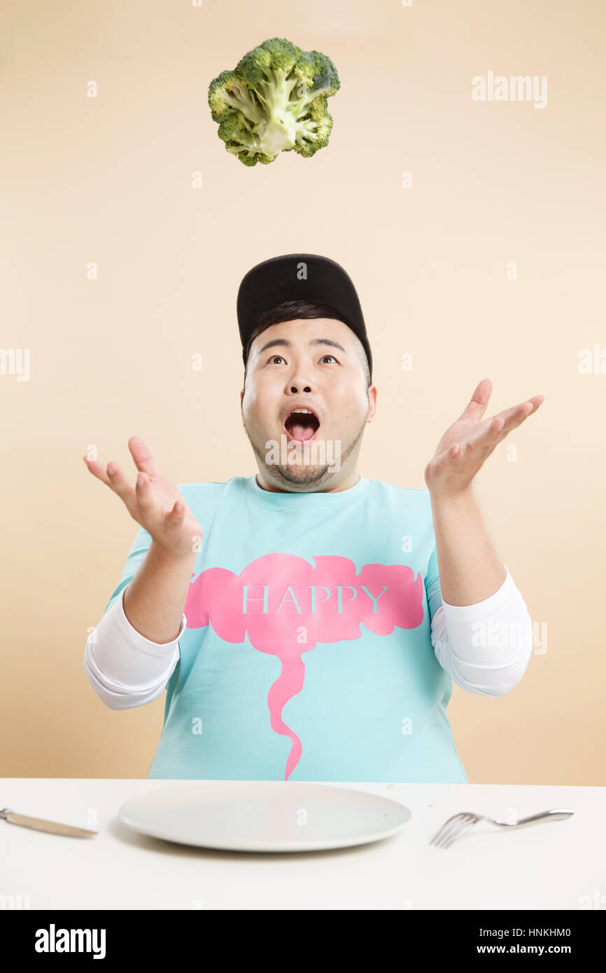 Small fat man throwing broccoli Stock Photo - Alamy