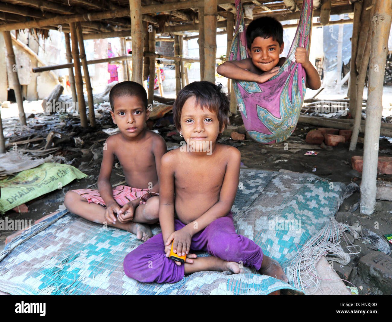 Children in Tangra Slum in Calcutta sit under a hut on stilts, India ...