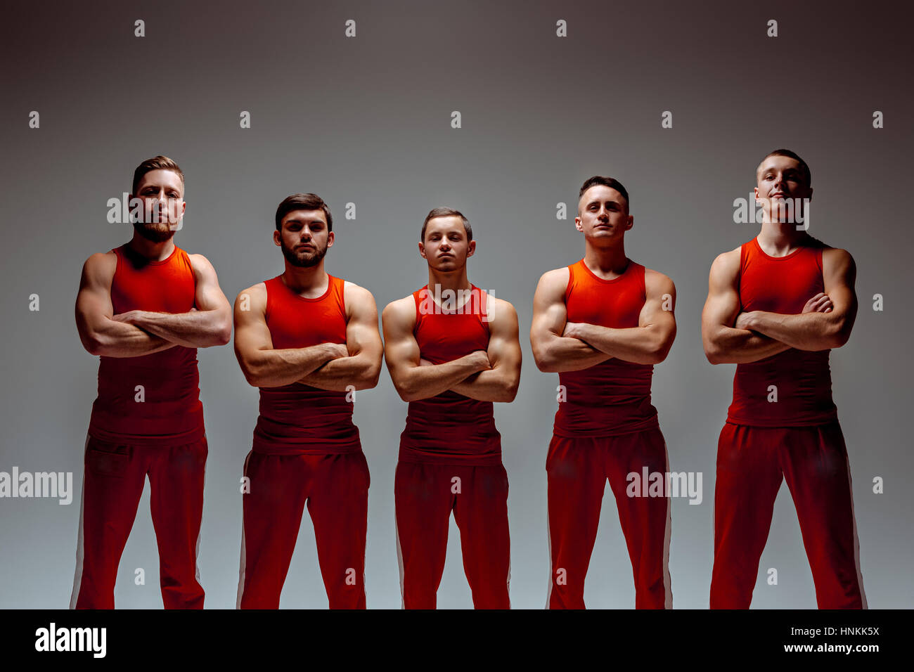 The group of gymnastic acrobatic caucasian men posing on gray studio ...