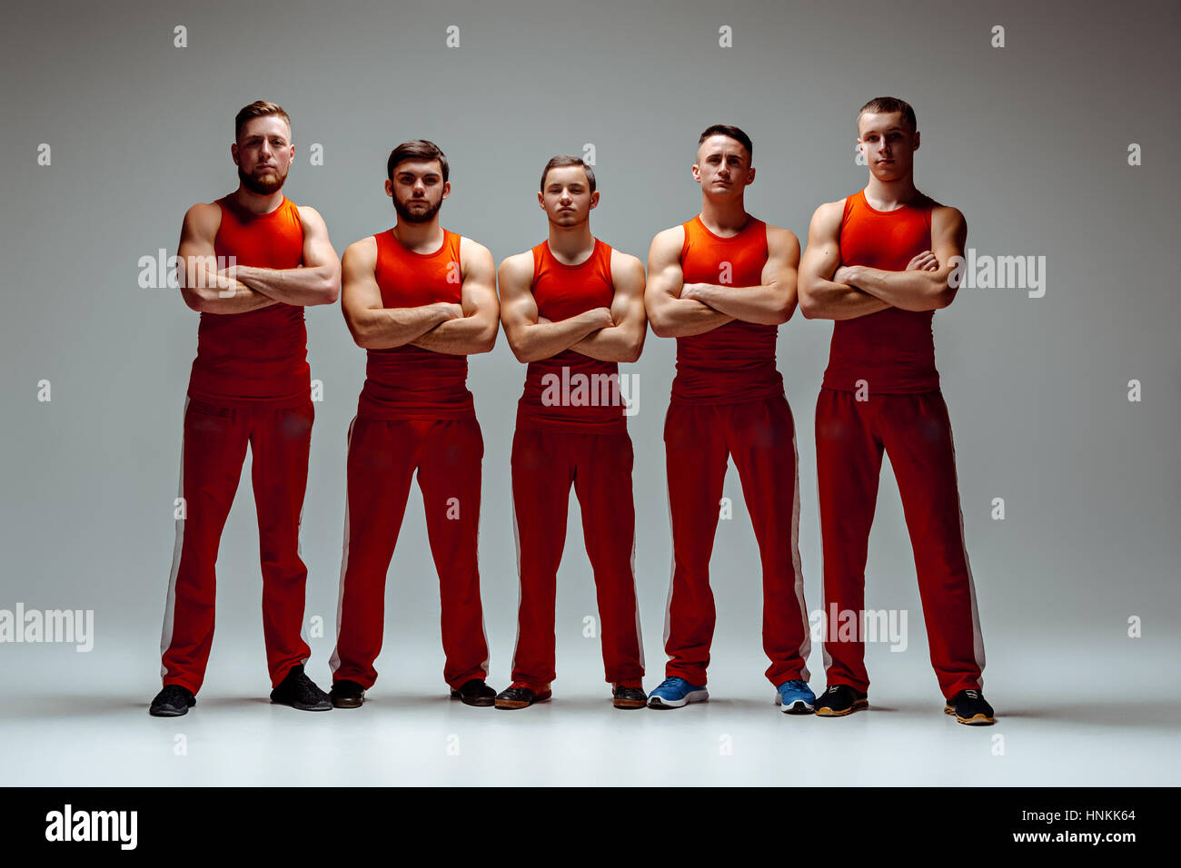 The group of gymnastic acrobatic caucasian men posing on gray studio ...