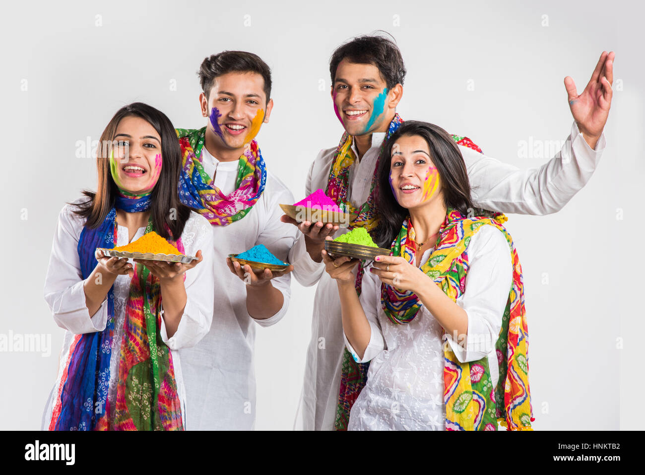 4 smart young indian people celebrating holi, standing isolated over ...