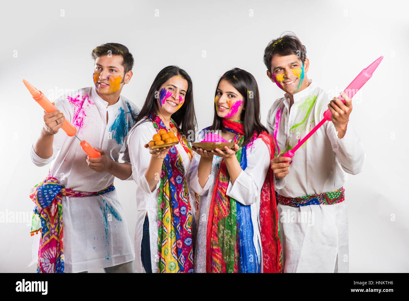 4 smart young indian people celebrating holi, standing isolated over ...