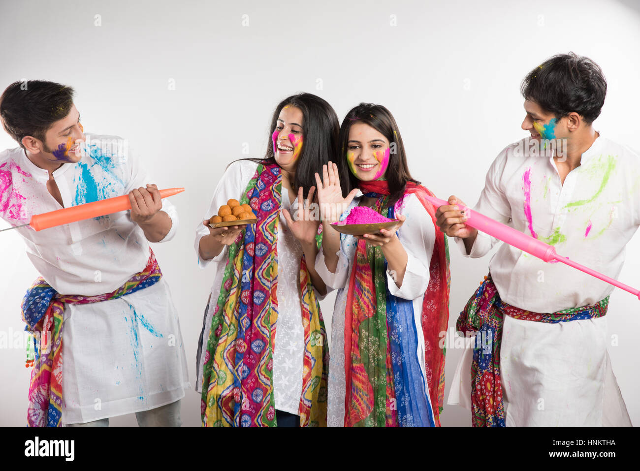 4 smart young indian people celebrating holi, standing isolated over ...
