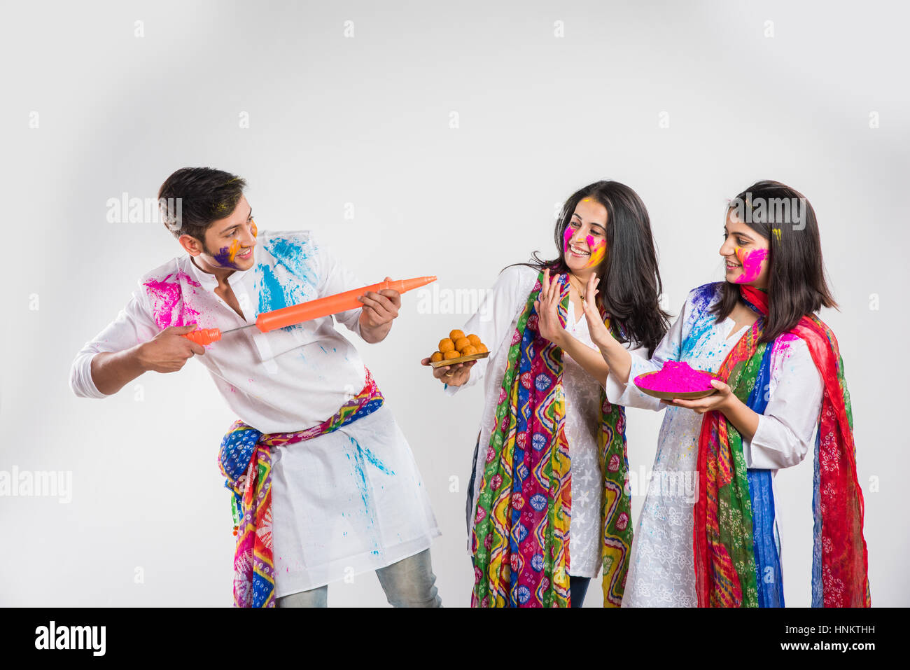 4 smart young indian people celebrating holi, standing isolated over ...