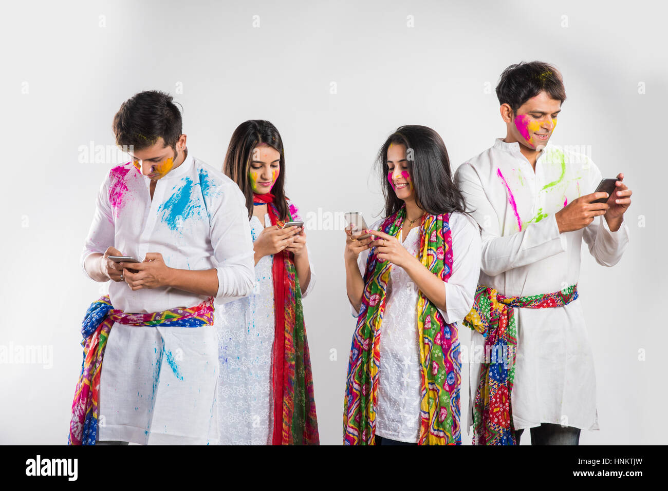 4 smart young indian people celebrating holi, standing isolated over ...