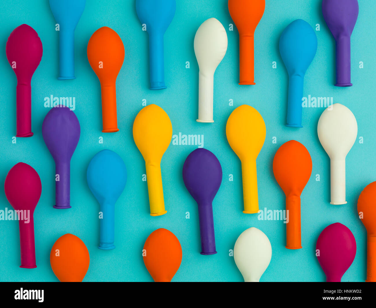 arranged pattern of colorful deflated balloons on a blue background ...