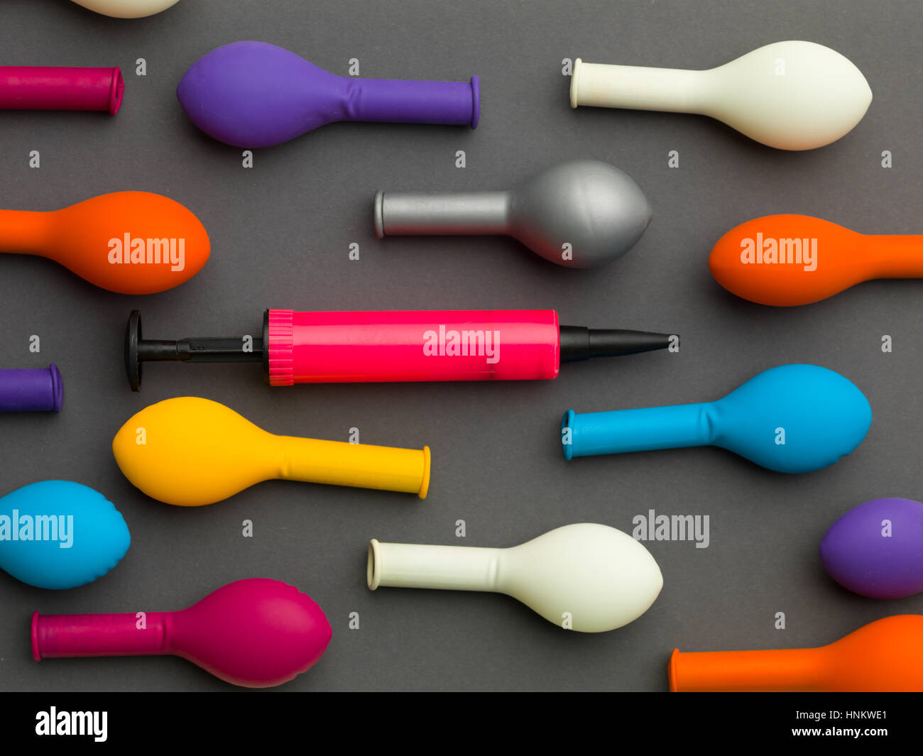 pink balloon pump between colorful deflated balloons, on a grey ...