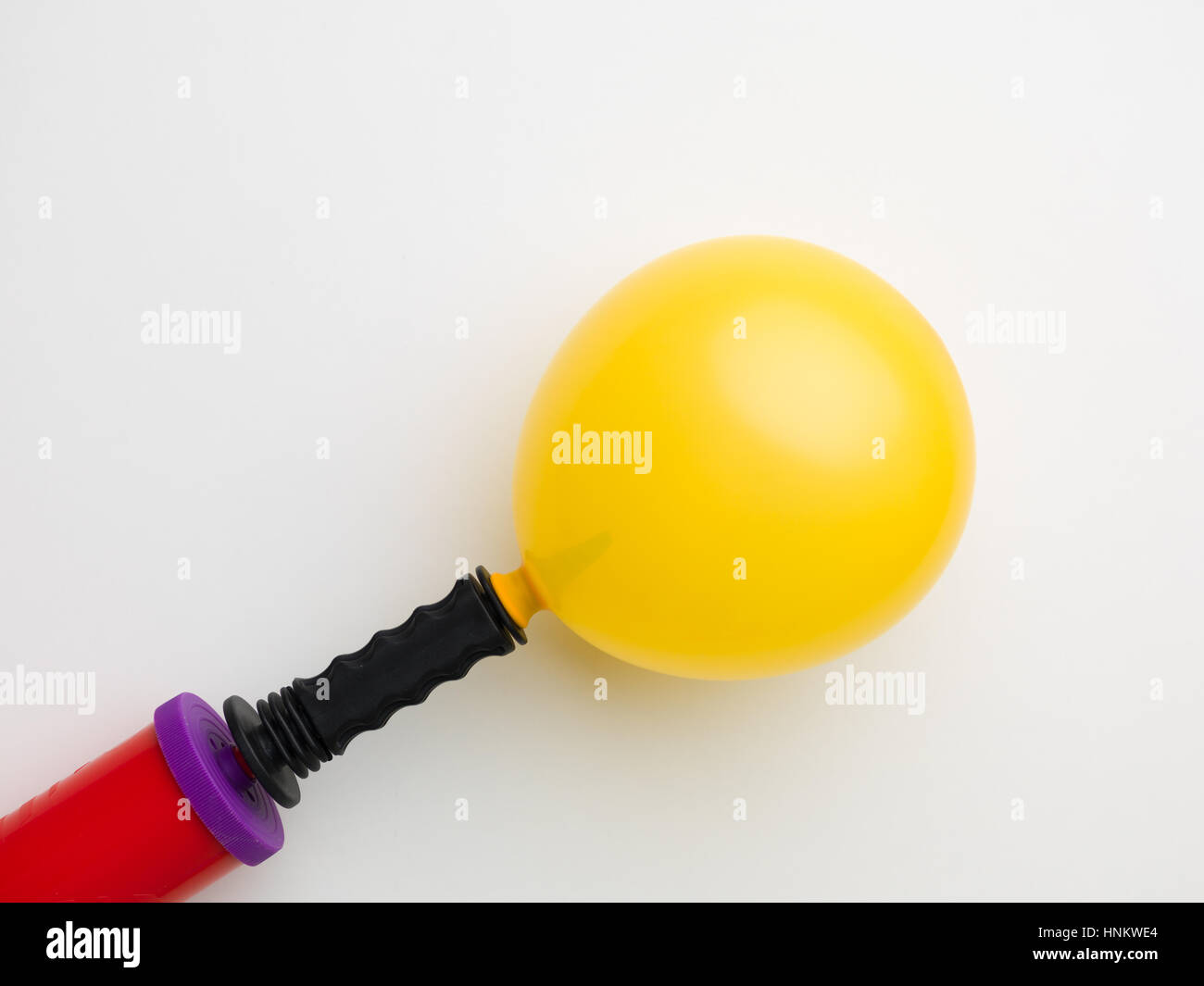 red air-pump inflating a yellow ballon on a white background Stock ...