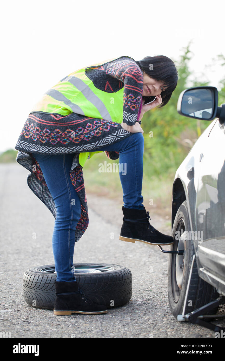 Woman changing a wheel on a car on the empty road, Selective focus and ...