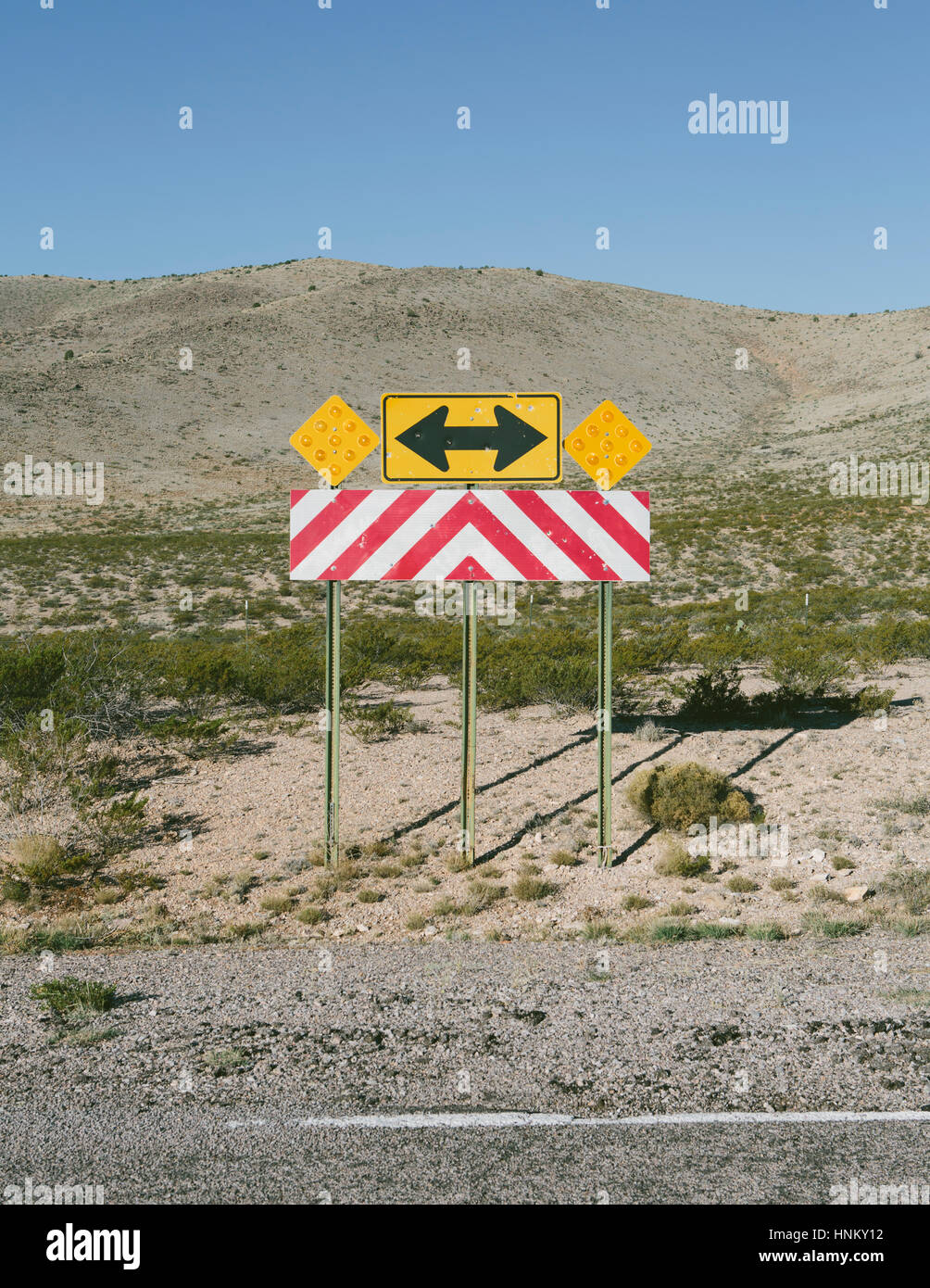 Directional arrow and caution sign along rural desert road Stock Photo ...