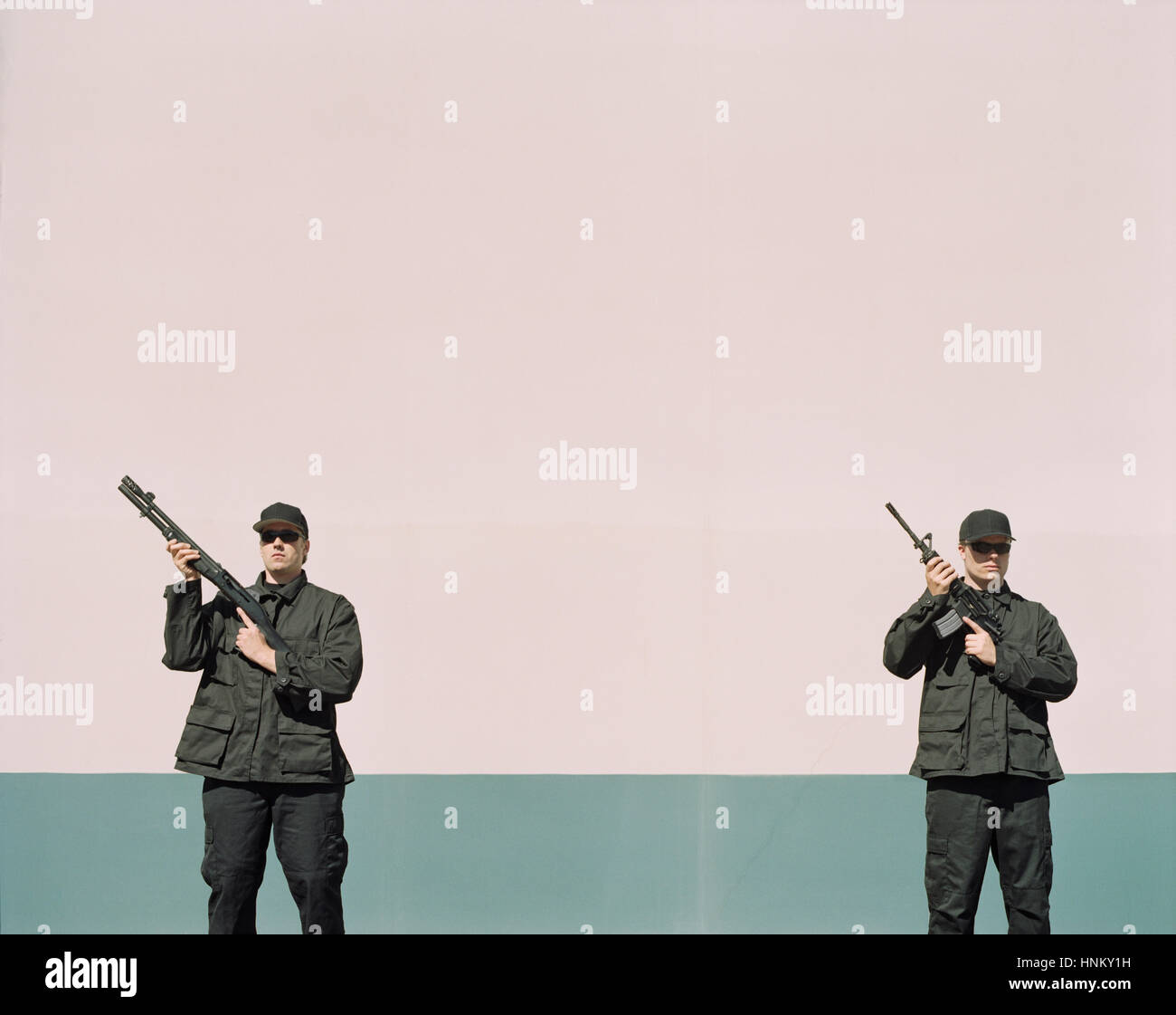 Two men wearing special forces uniforms, holding high powered guns ...
