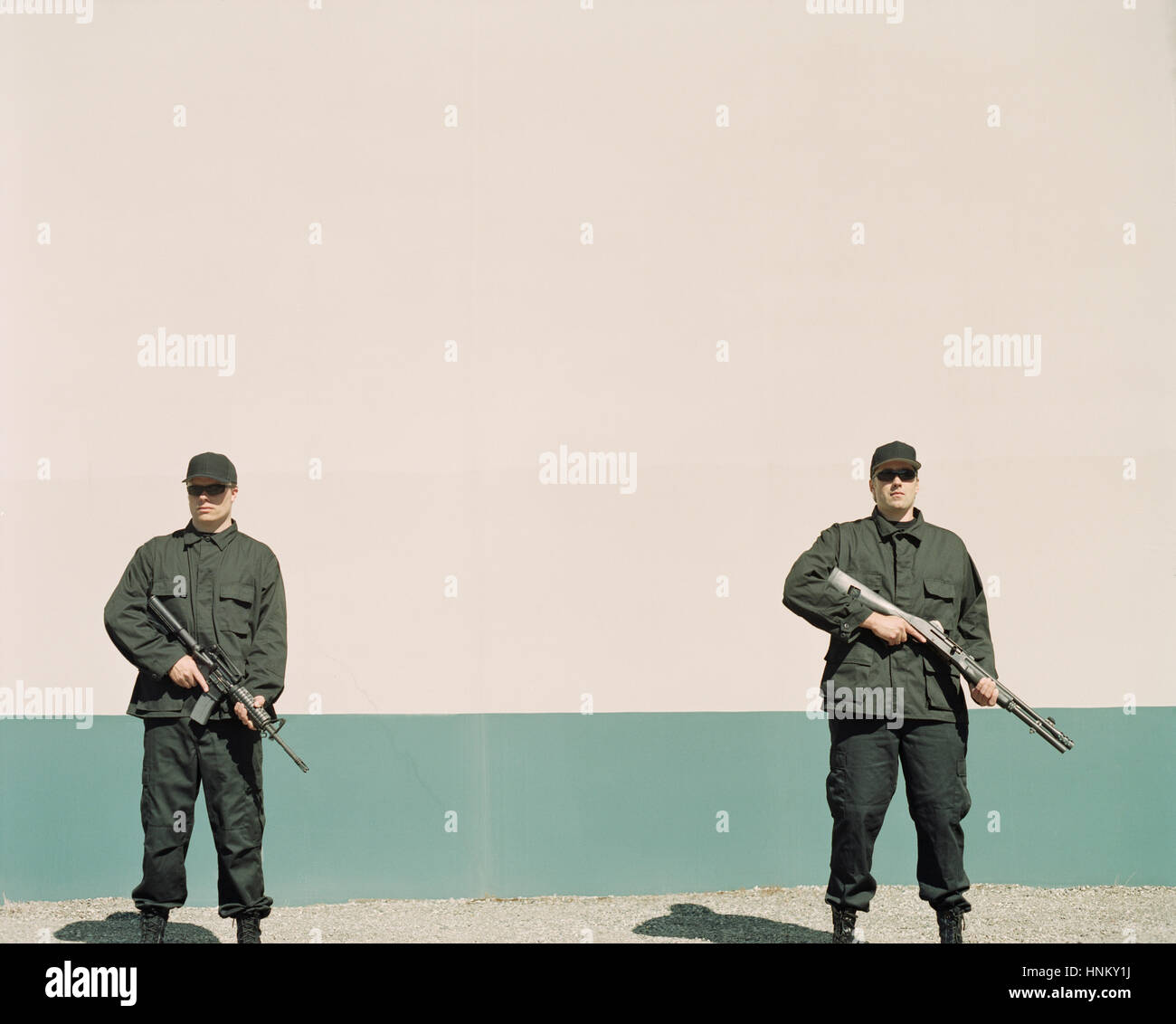 Two men wearing special forces uniforms, holding high powered guns ...