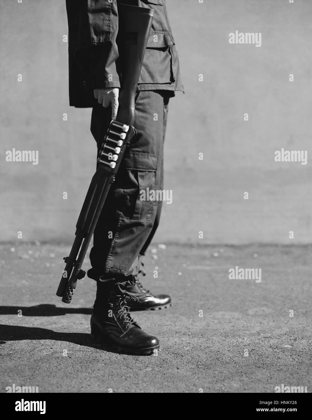 Cropped view of man in special forces, holding high powered shotgun ...